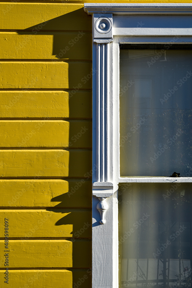 exterior view of white painted window frame of yellow Victorian house ...