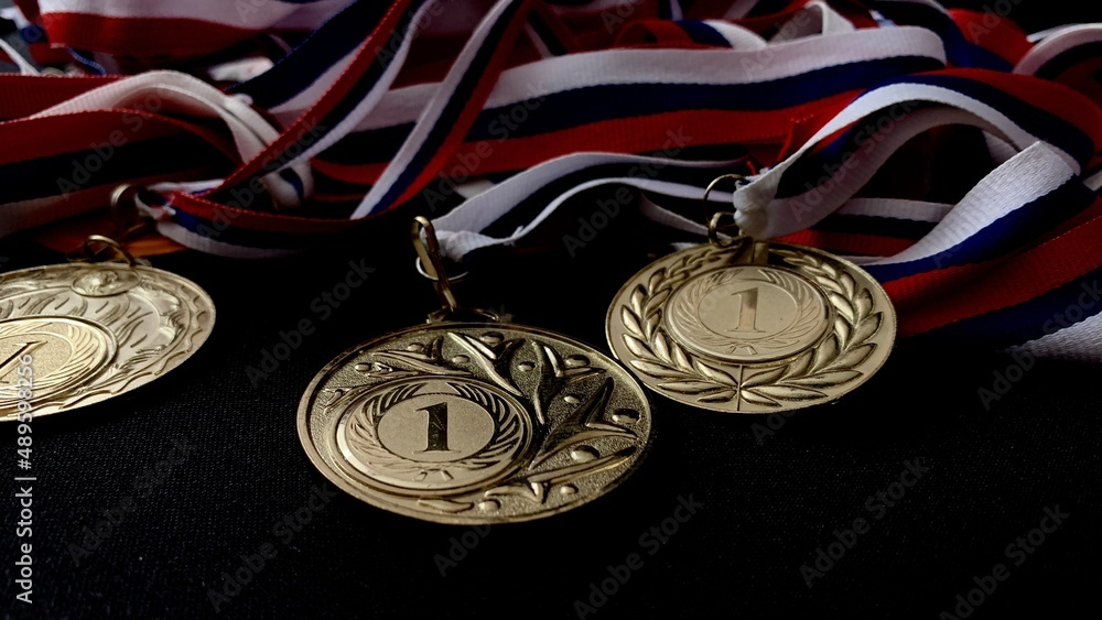 Gold, silver, bronze medals and cups on a black background. A large ...