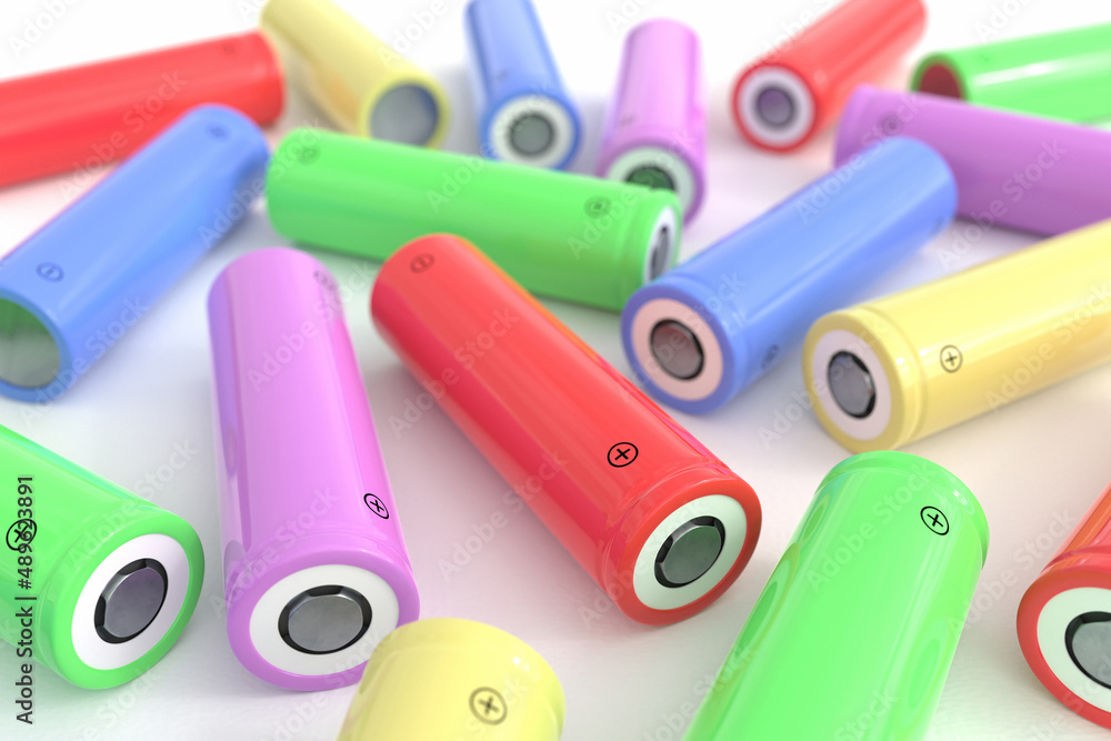 Cylindrical batteries of various colors on a white table. Compact ...