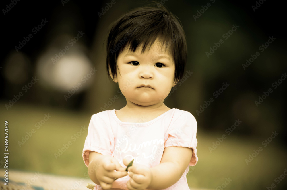 Cute baby Thai girl feel happy and relaxing , sitting on the grass in ...