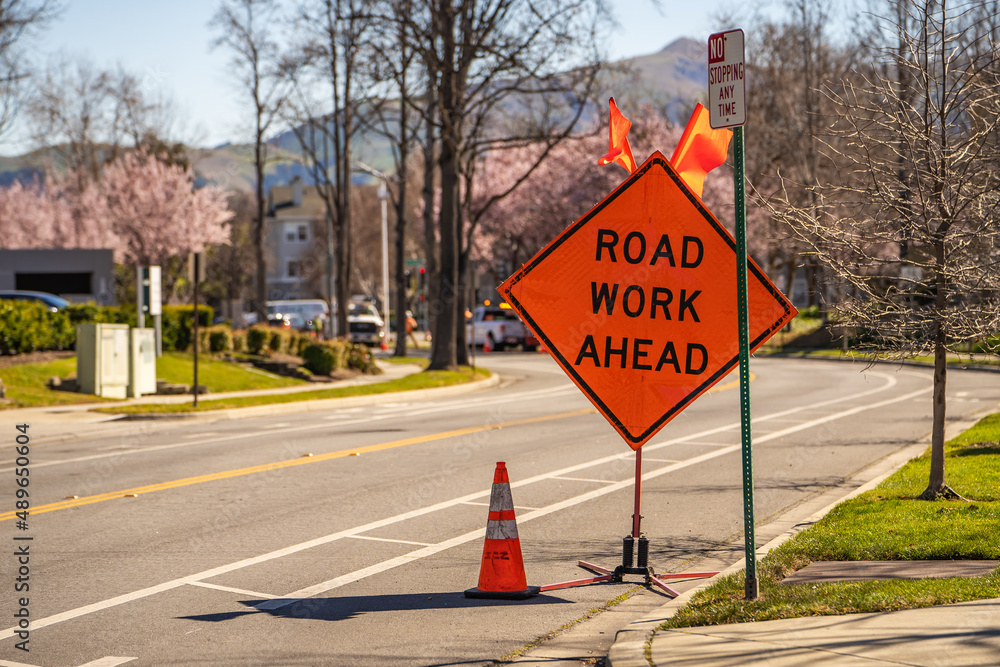 Traffic sign with flags says: "Road work ahead". Orange diamond road ...