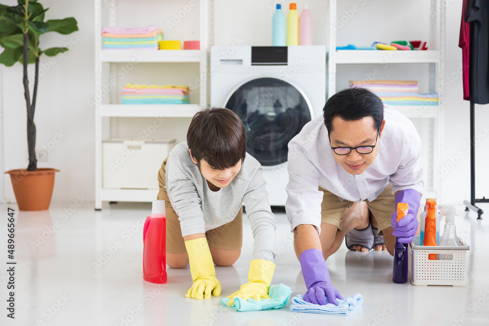 Asian father and son help each other to clean the floor for daily ...