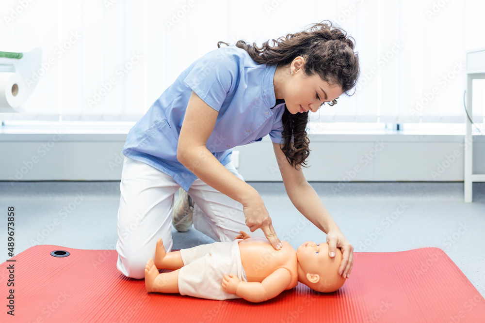 Foto de Woman performing CPR on baby training doll with one hand ...