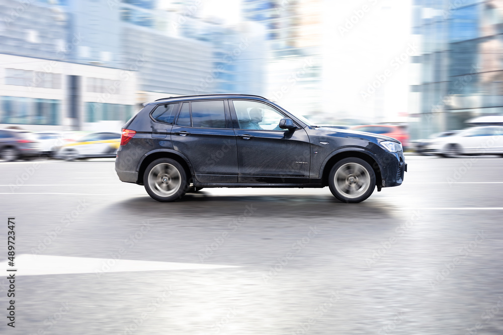 Fast moving BMW X3 F25 on the city road. Black SUV with man driving ...