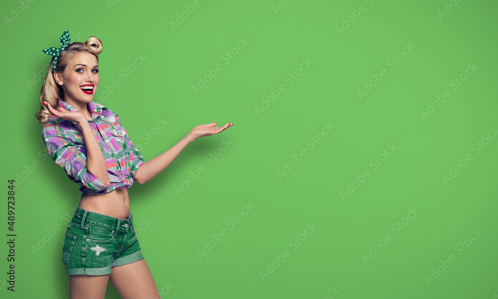 Woman holding, pointing or giving something. Excited girl in pin up ...