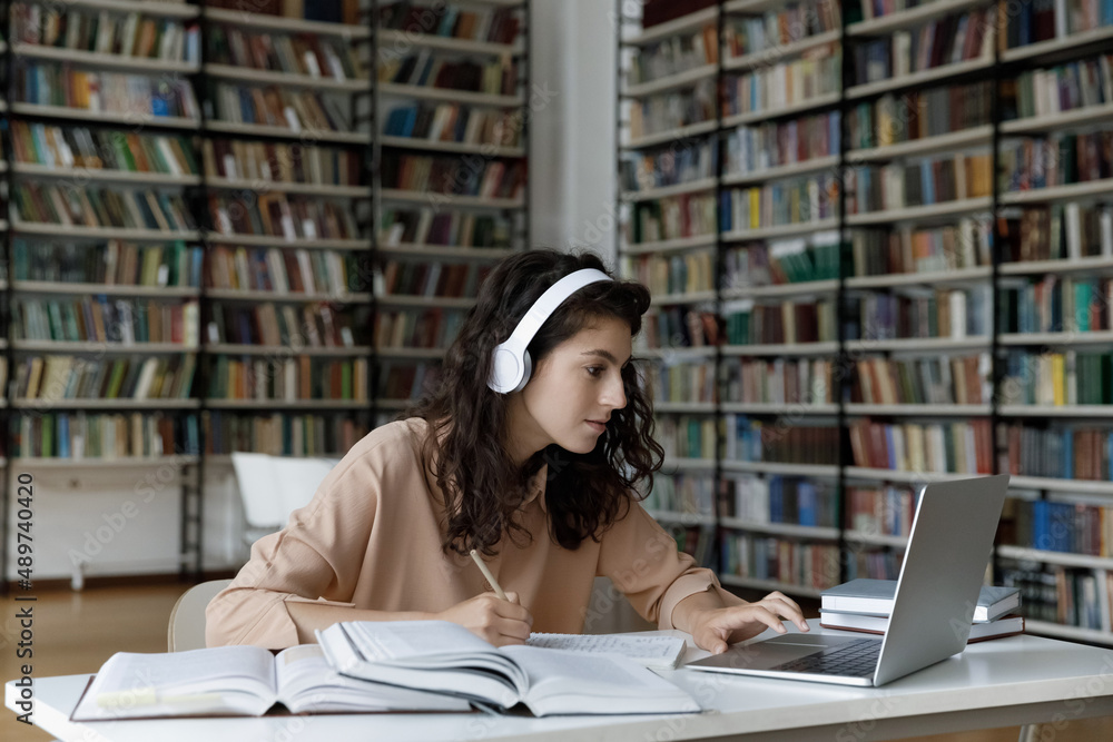 Happy pretty millennial Hispanic female student in headphones, using ...