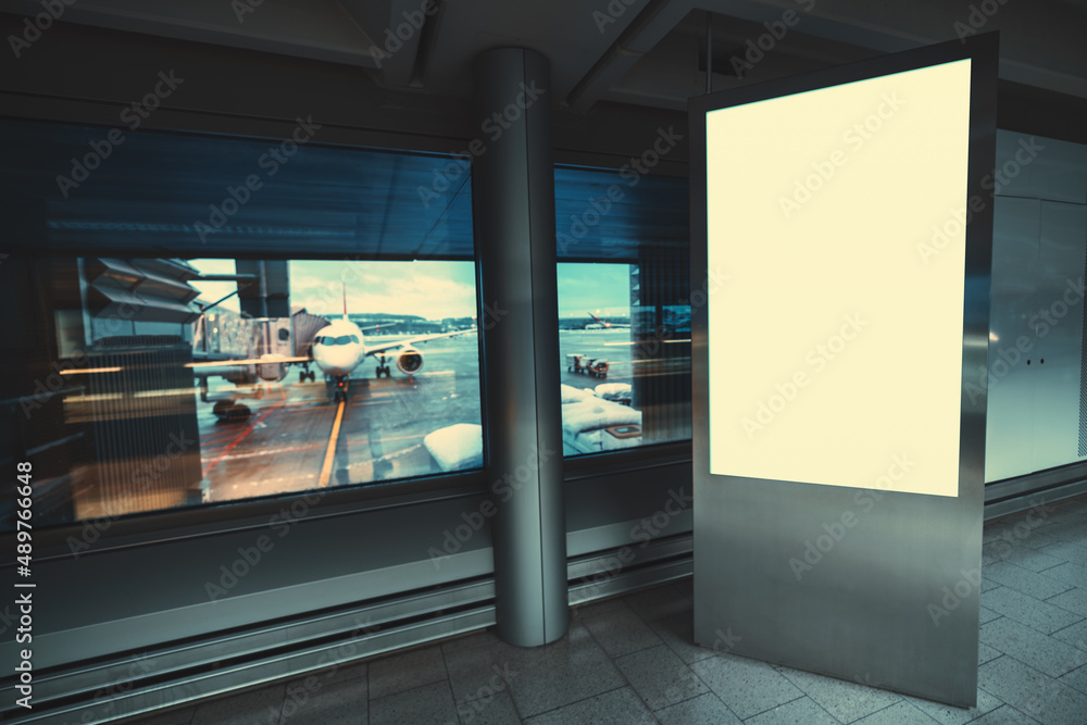 A vertical empty ad billboard mock-up in an airport hall with an ...