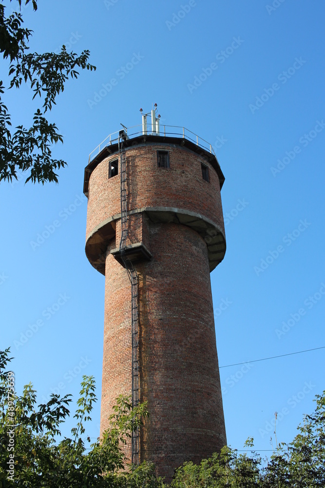 round brick water tower ancient architecture in a park with trees in ...