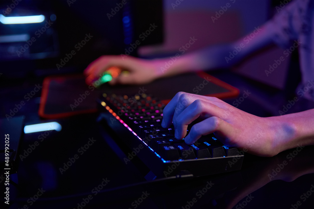 Teenaeger boy play computer video game in dark room, use neon colored ...