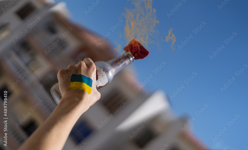 female hand-painted in Ukraine flag colors in a fight with a burning ...