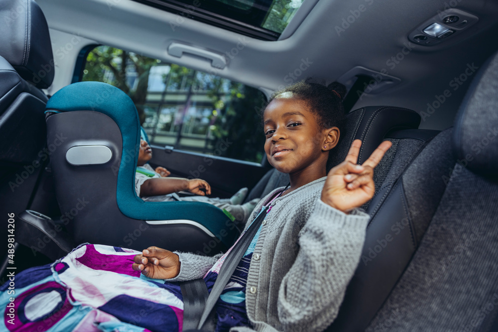 Smiling girl doing peace sign sitting in car Stock Photo | Adobe Stock
