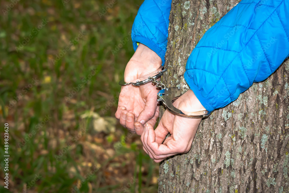 The girl is tied to a tree with handcuffs. Violence. Stock Photo ...