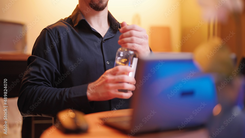 Headless person behind the laptop computer drink water from glass ...