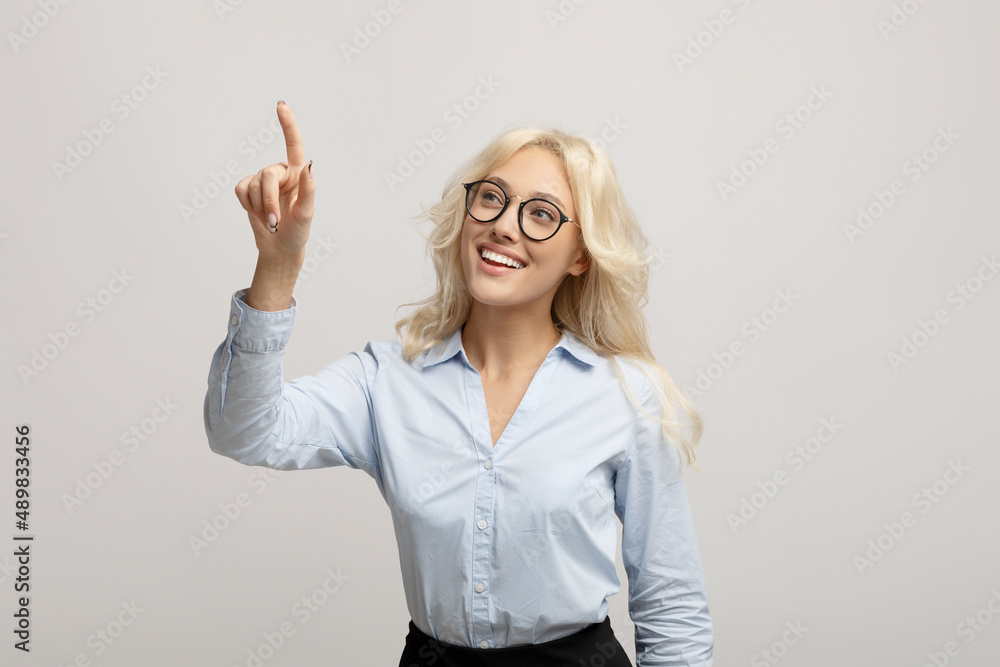 Happy female entrepreneur pushing button on virtual screen over light ...