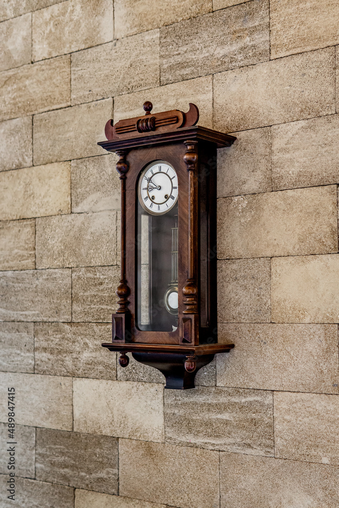 Wall vintage wooden clock with a pendulum on a brick wall. Mechanical ...