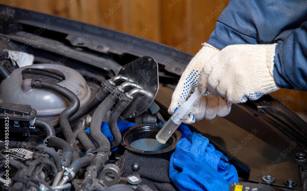 The mechanic sucks old fuel out of the fuel filter with a syringe ...