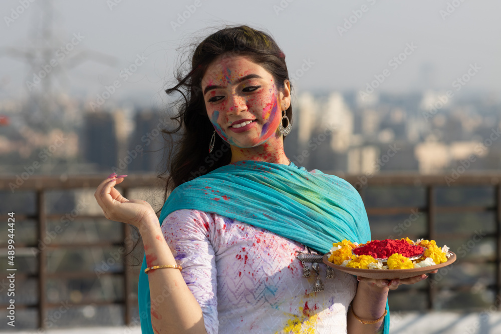 Young smart indian girl with plate full of color powder and face ...