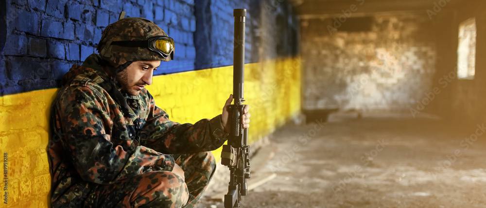 Military soldier on the background of the flag of Ukraine. The flag of ...