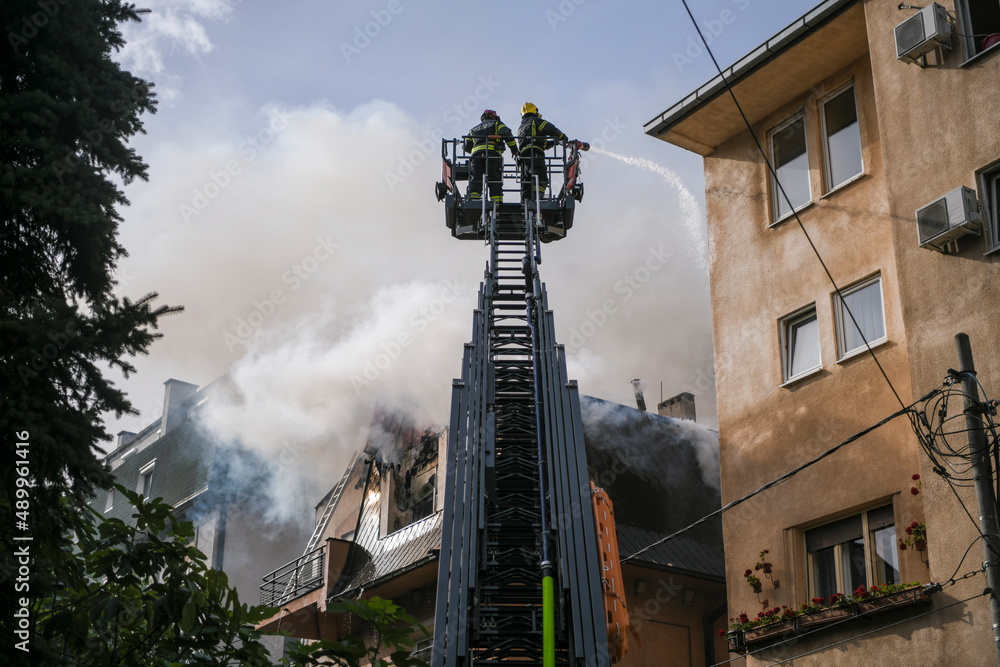 Dramatic scene of Firefighters rising on a mechanical sliding ladder ...