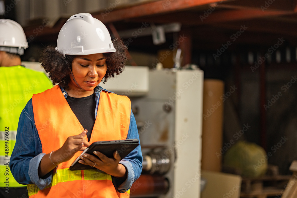 Engineer asian and african woman wearing safety helmet and vest holding ...