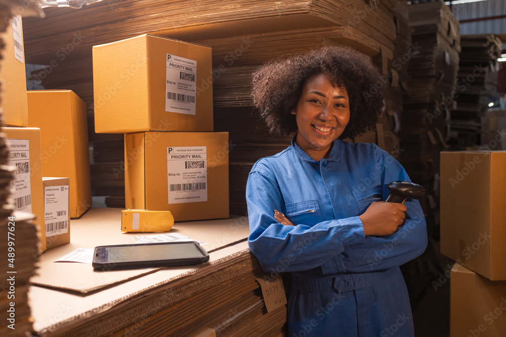 African American worker working in storage, taking parcel and scanning ...