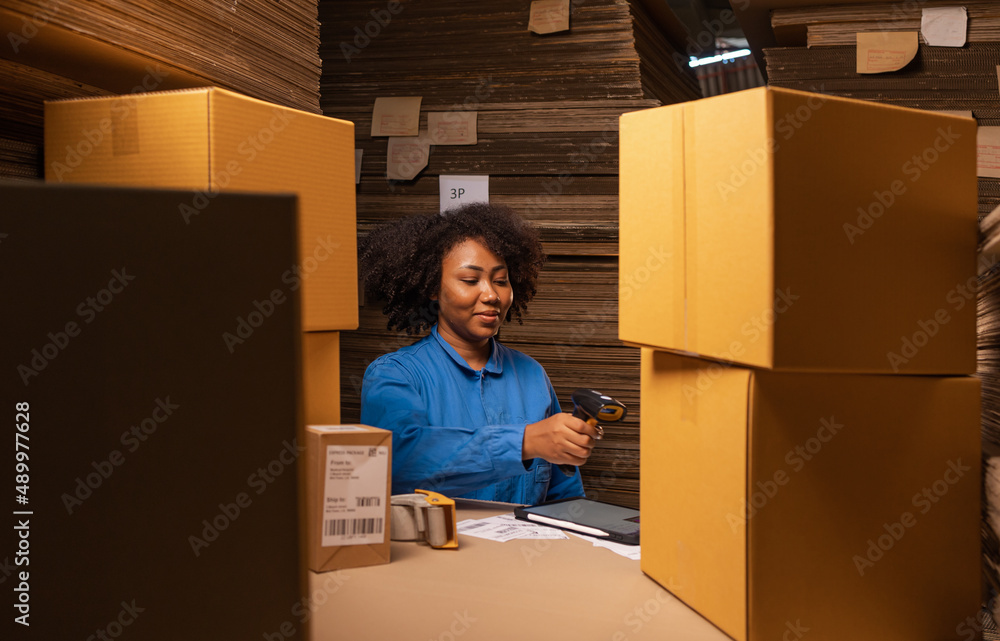 African American worker working in storage, taking parcel and scanning ...