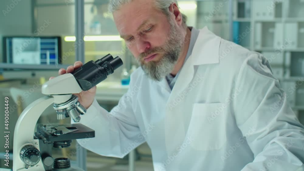 Tilt up shot of senior Caucasian scientist with grey hair and beard ...