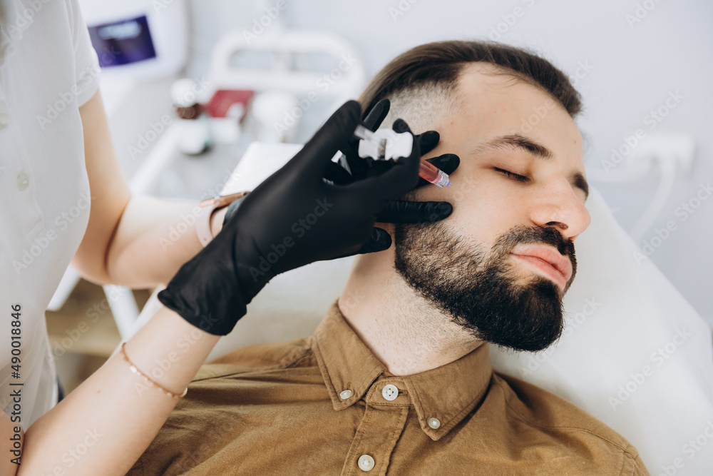 Stylish bearded man visiting aesthetic clinic, getting lips filler ...