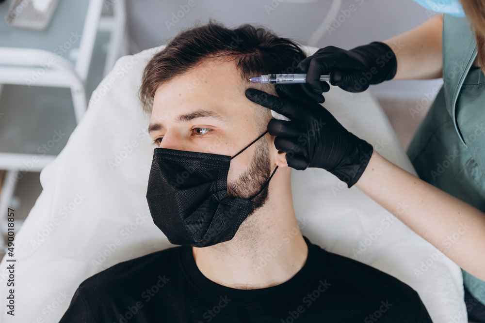 An attractive man receives mesotherapy injections to treat hair loss at ...