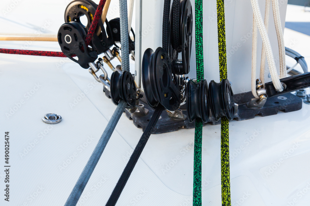Part of the mast and hull of a sailing yacht, with multi-colored ropes ...