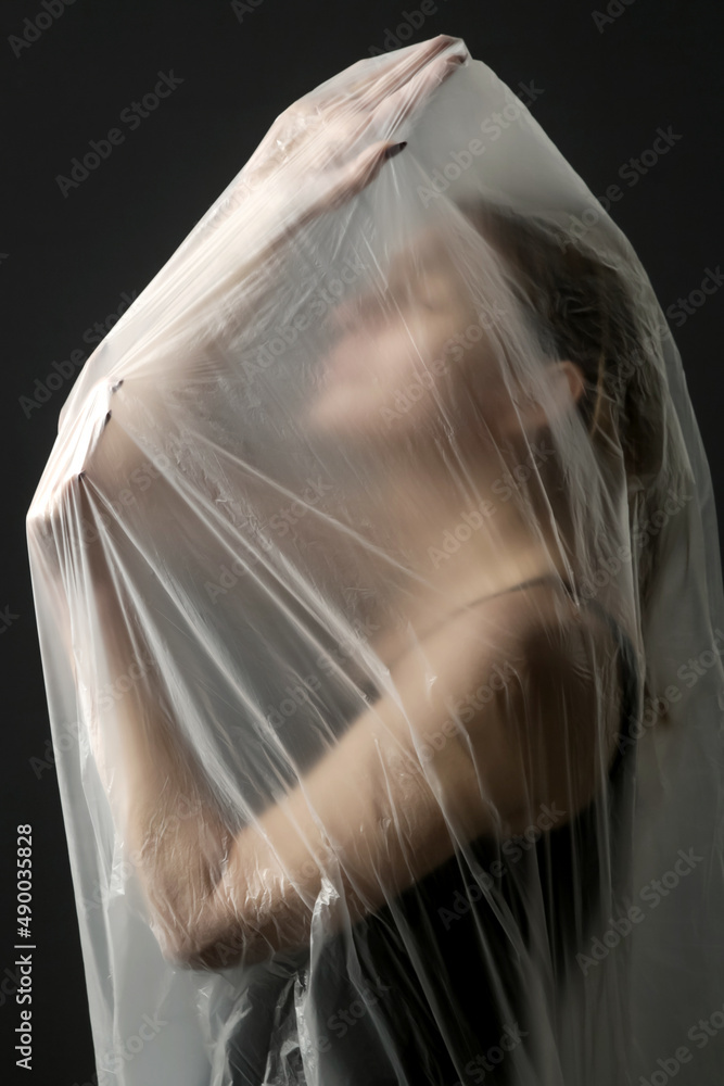 Woman wrapped in plastic sheet. Studio shot. Woman and mental health ...