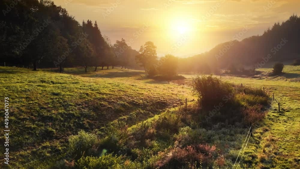 The sun rising over beautiful rural landscape surrounded by forests ...