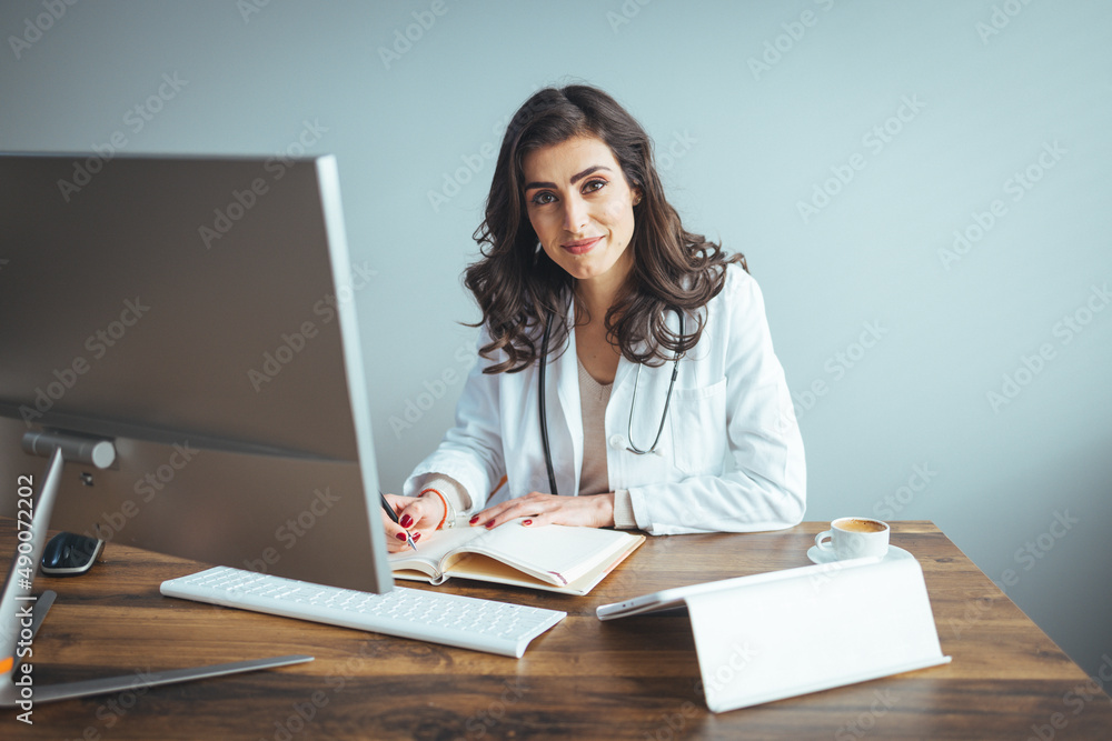 The mid adult female doctor reviews her patient's records on her ...