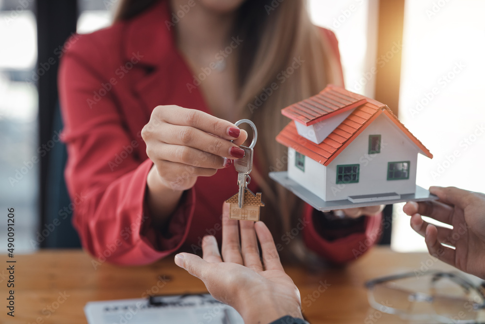 Real estate agent giving house key to the client after signing the real ...