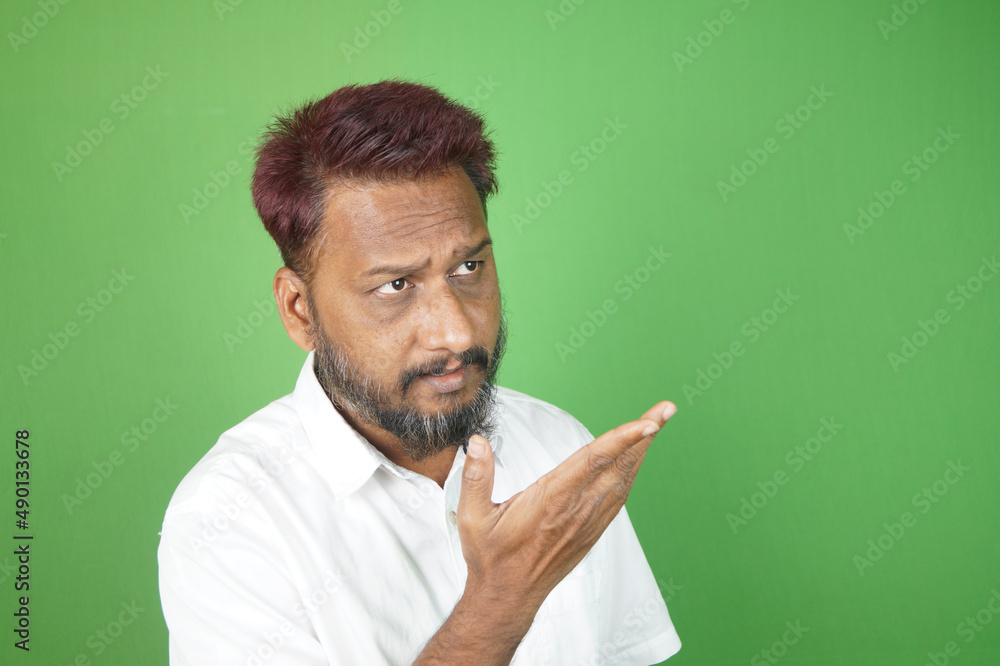 Indian adult man standing with his hand up on the green background ...