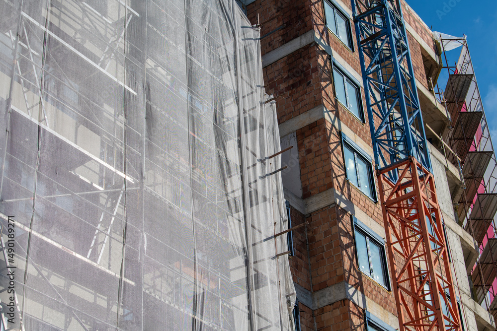 Net wrap or protective mesh covering scaffolding of multi-story ...