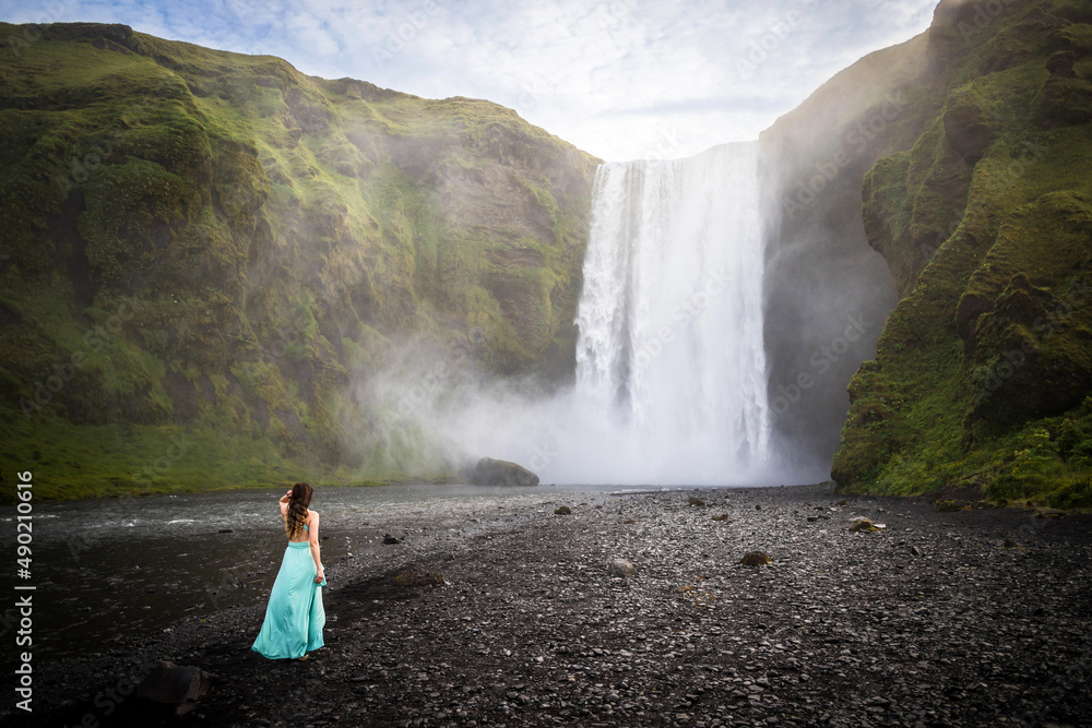 Beautiful scenery of a woman with long dress walking towards a tall ...