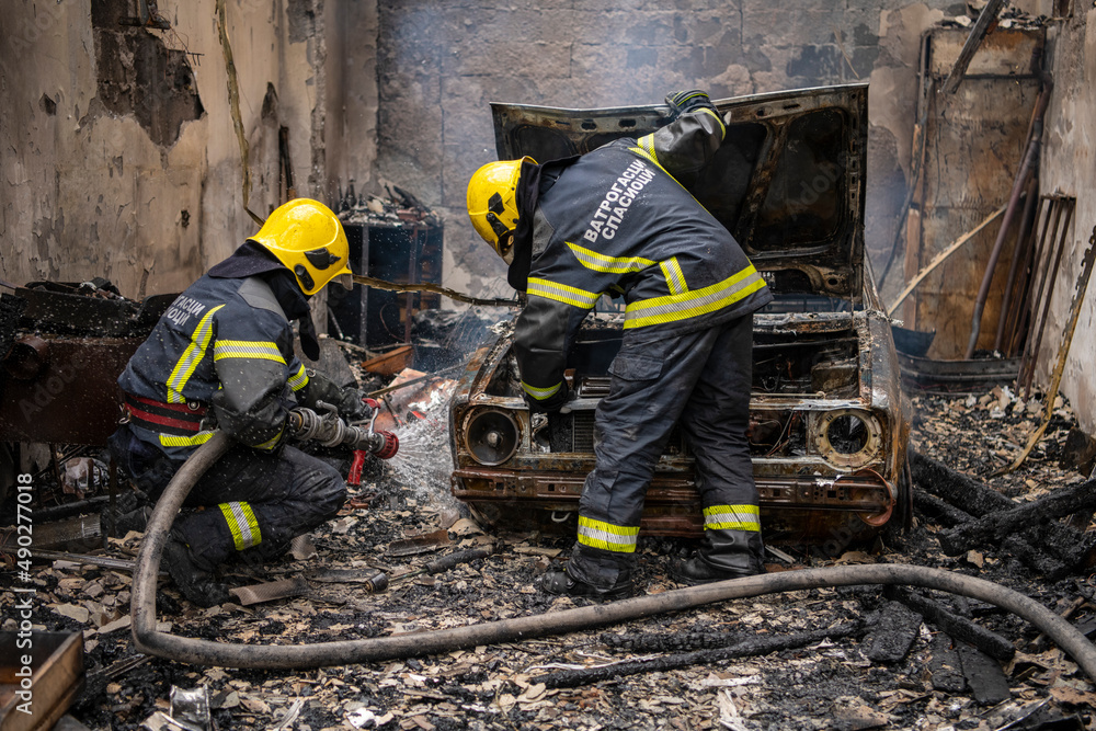 A car fire in workshop or house garage. Firefighters extinguishing fire ...
