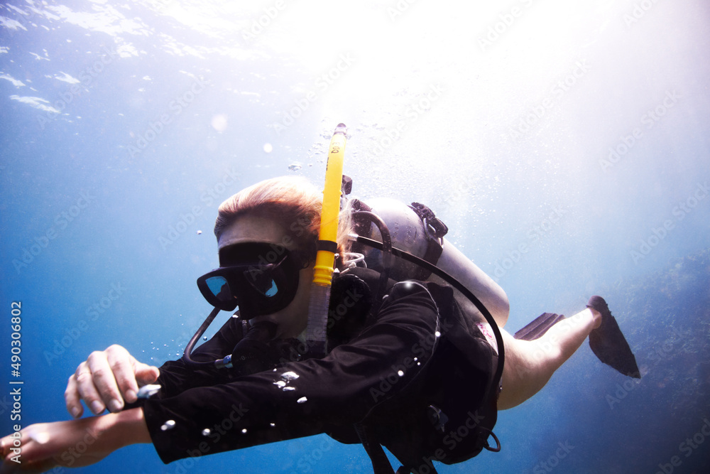 Time to descend. Young female scuba diver floating through the water as ...