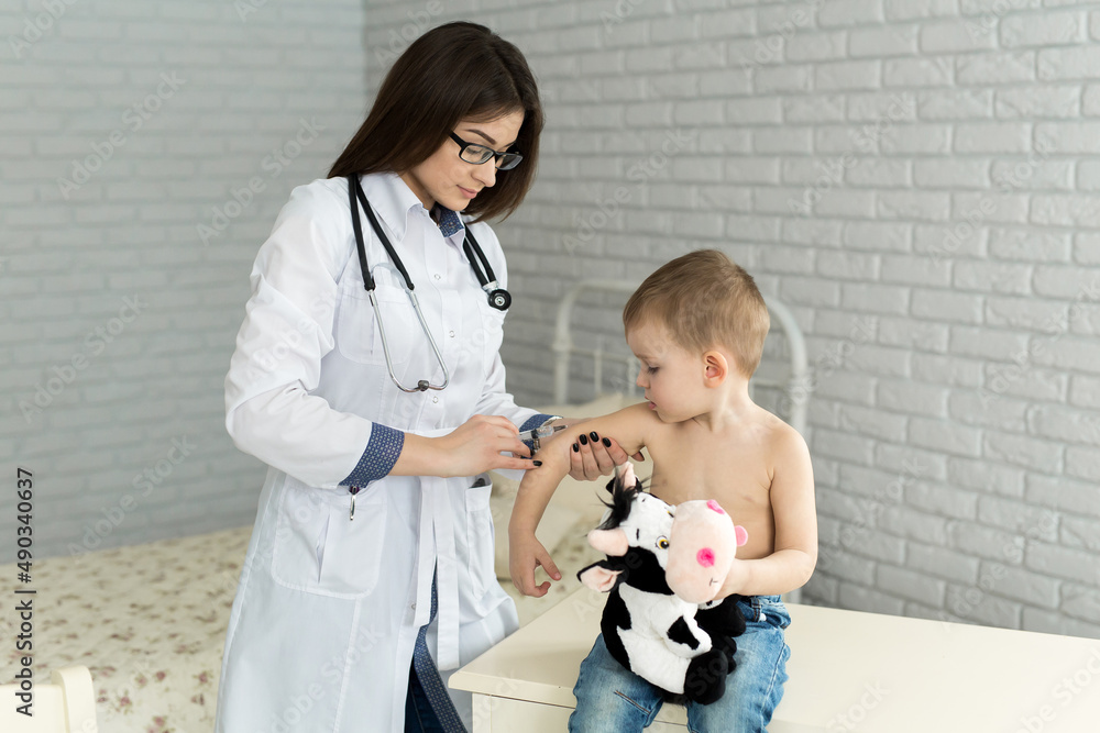 Doctor pediatrician giving child an intramuscular injection in arm ...