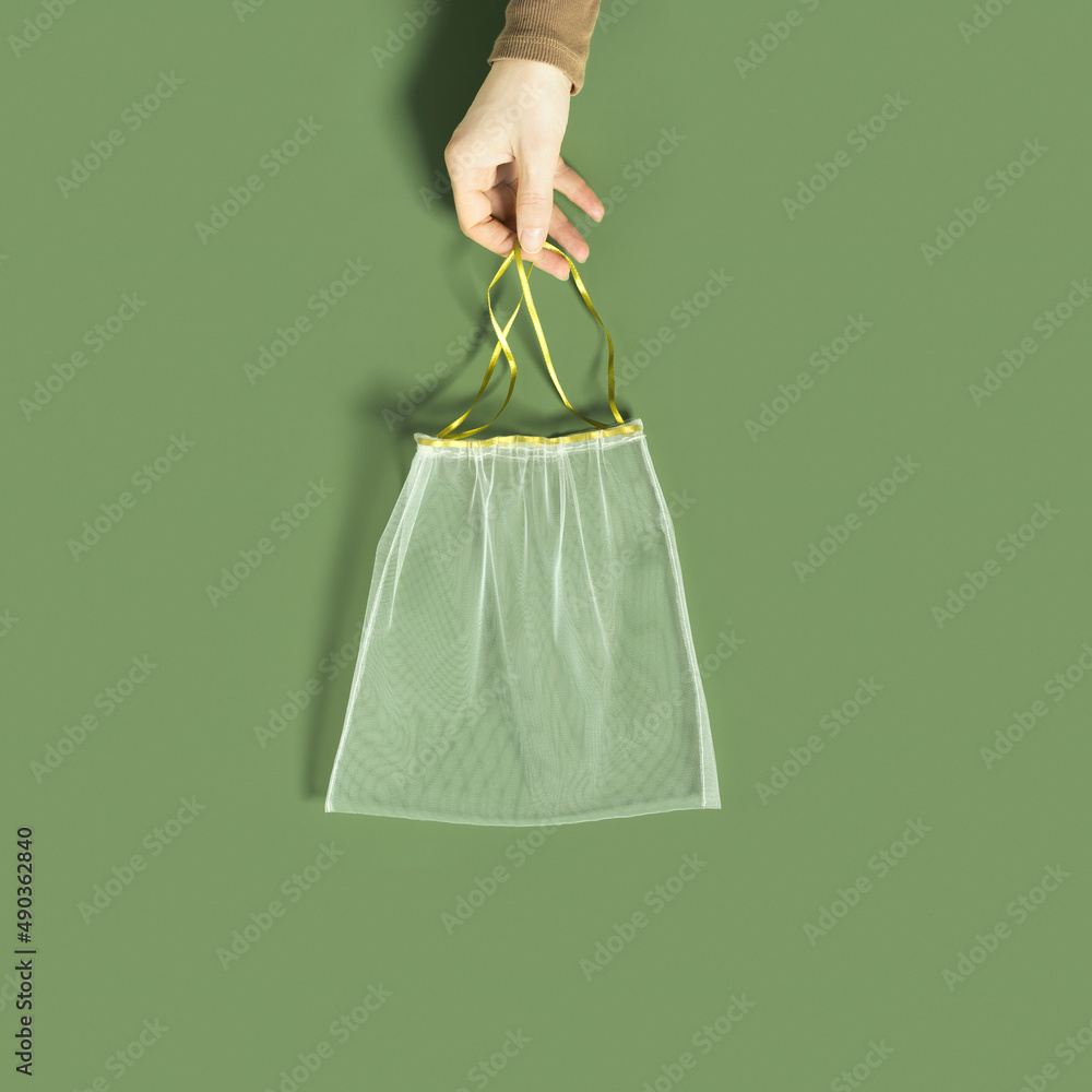 Hand holding reusable grocery bags from net, reusable packaging for ...