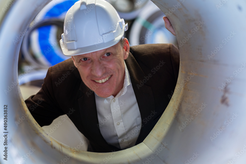 factory owner, wearing an engineer helmet, smiles successfully, works ...