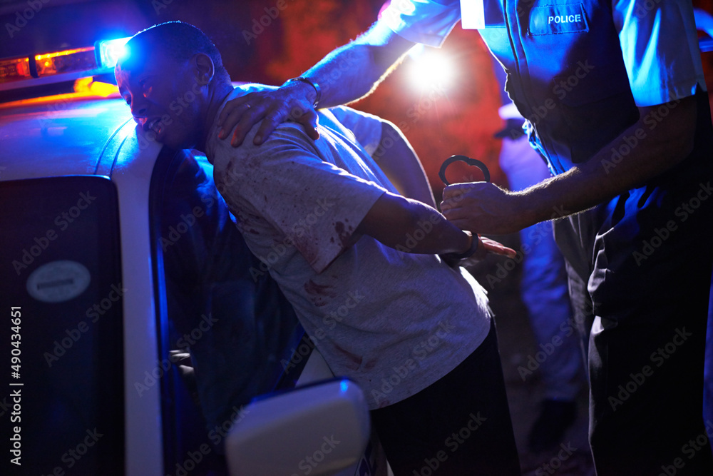 Foto de To serve and protect. Shot of a police officer handcuffing a ...