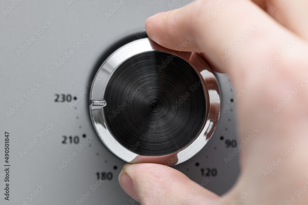Hand twists round temperature adjustment button in the microwave oven ...