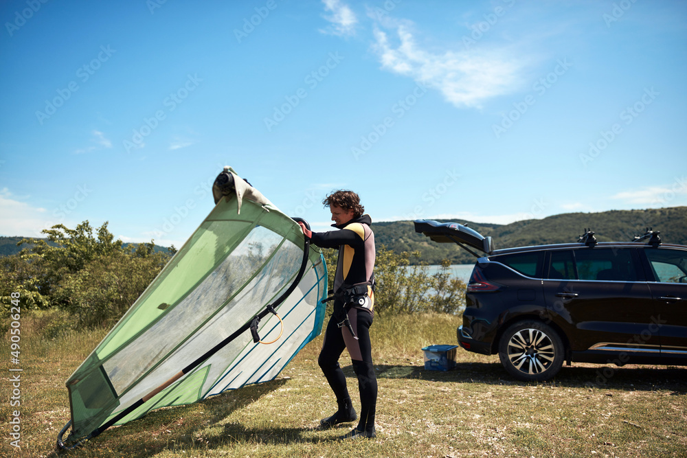 Windsurfer and camper packing and unpacking from a car's roof rack in ...