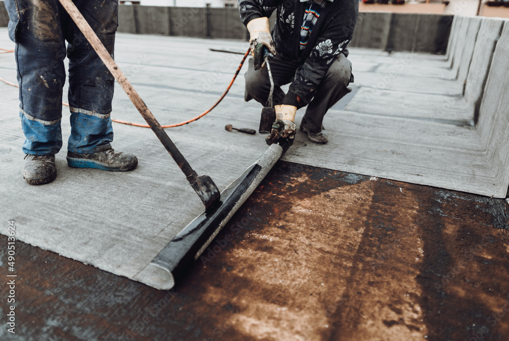 Rooftop terrace waterproofing details. Workers installing bituminous membrane waterproofing ...