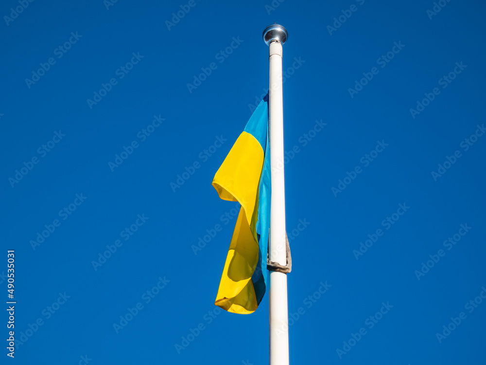 The blue and yellow Ukrainian flag flying in the sky on the flagpole in ...