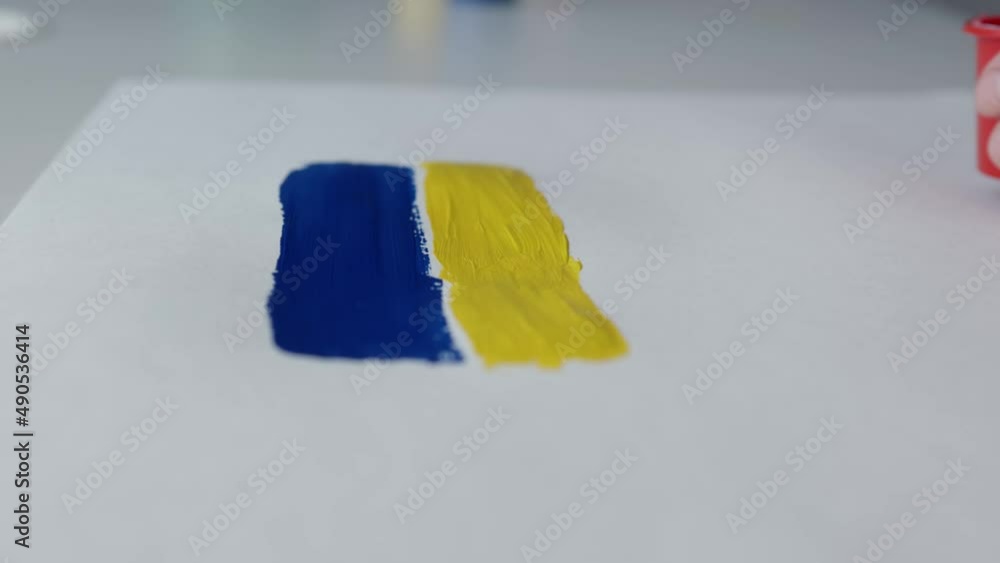 painting yellow blue Ukraine flag with drawing red heart around symbol ...