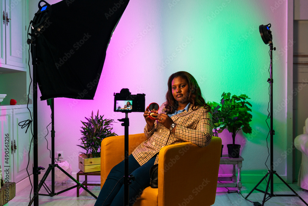 Curvy african american female vlogger in stylish outfit sitting in ...