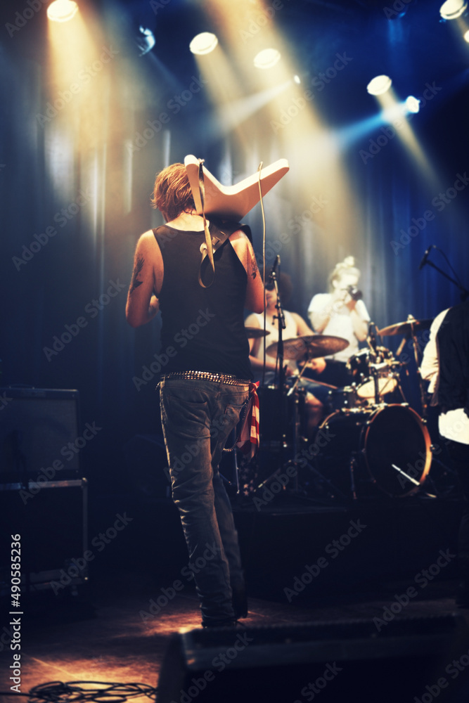 Rocking out. A guitarist on stage with his band beneath strobe lights ...